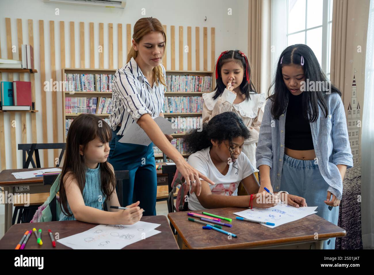 Students work together on art projects with guidance from a teacher in a bright, organized ...