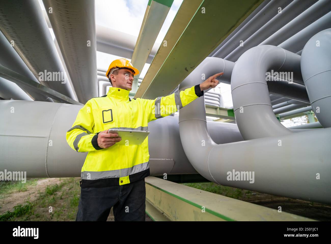 Engineer wearing a high-visibility jacket and helmet conducts a safety ...