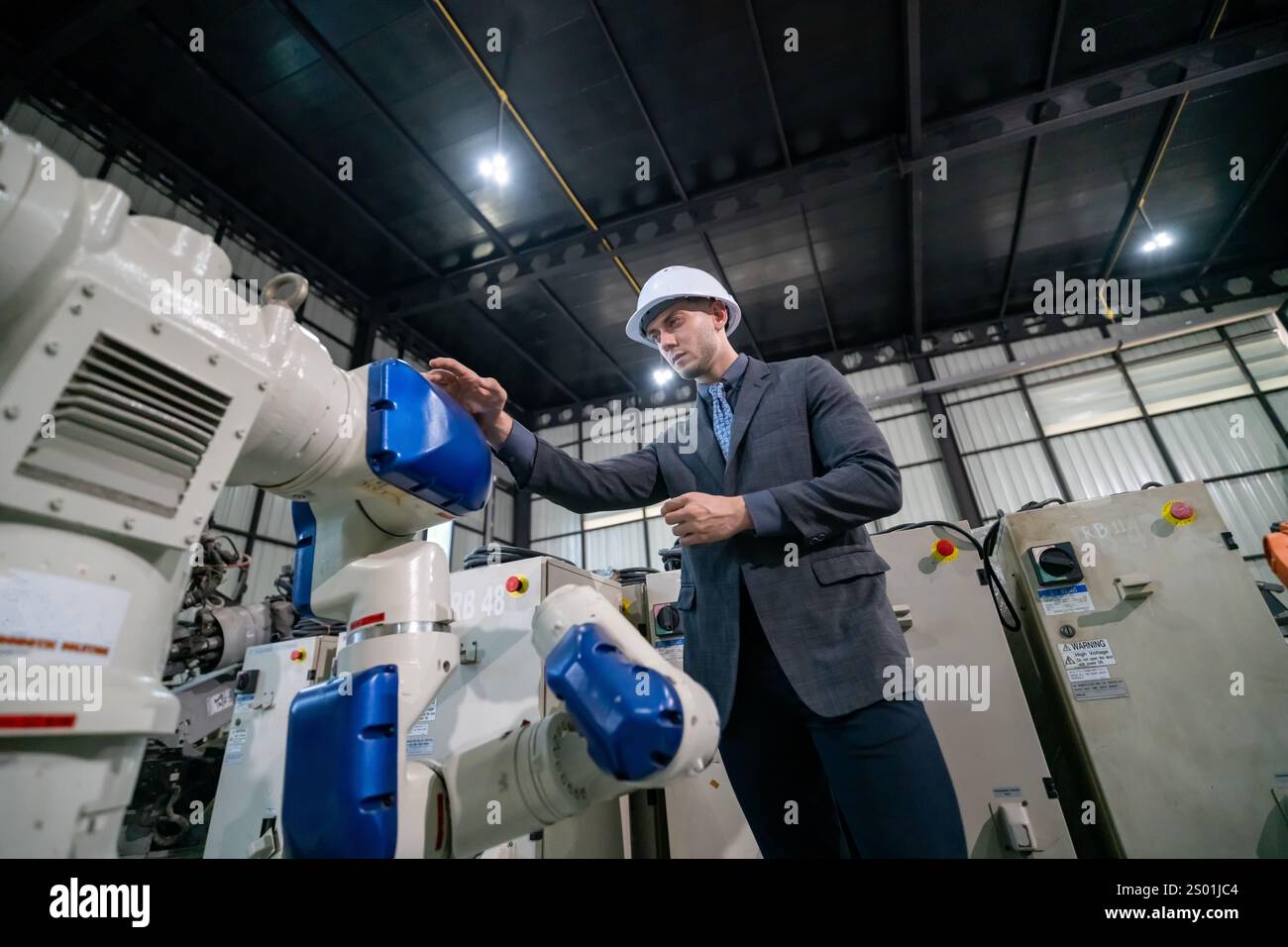 In a modern industrial setting, an engineer in formal attire and a ...