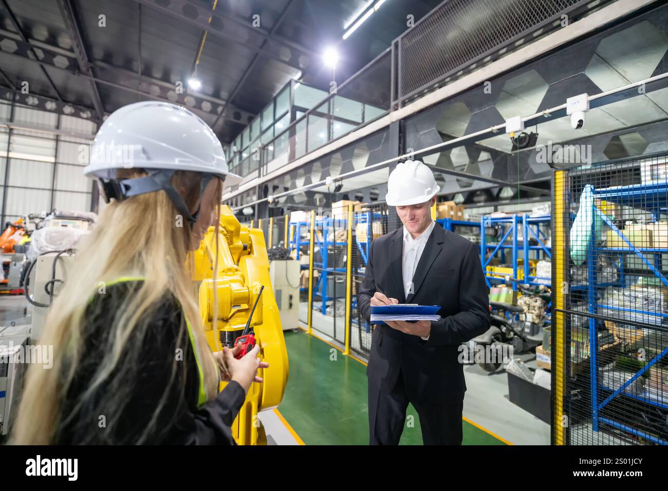 Two individuals in hard hats are engaged in a conversation within a ...