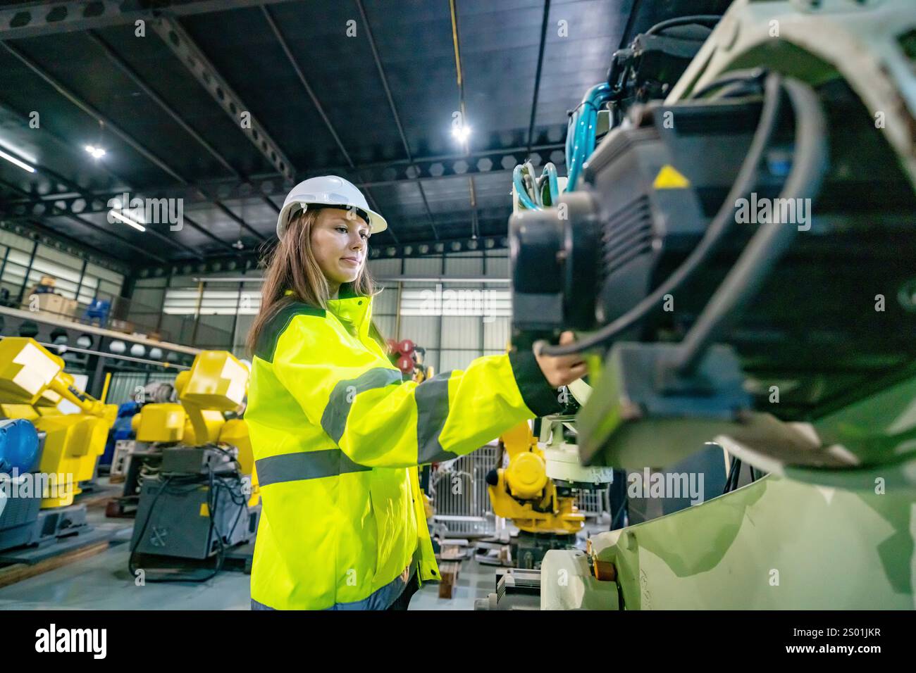 A woman in a bright yellow safety jacket and hard hat inspects and ...
