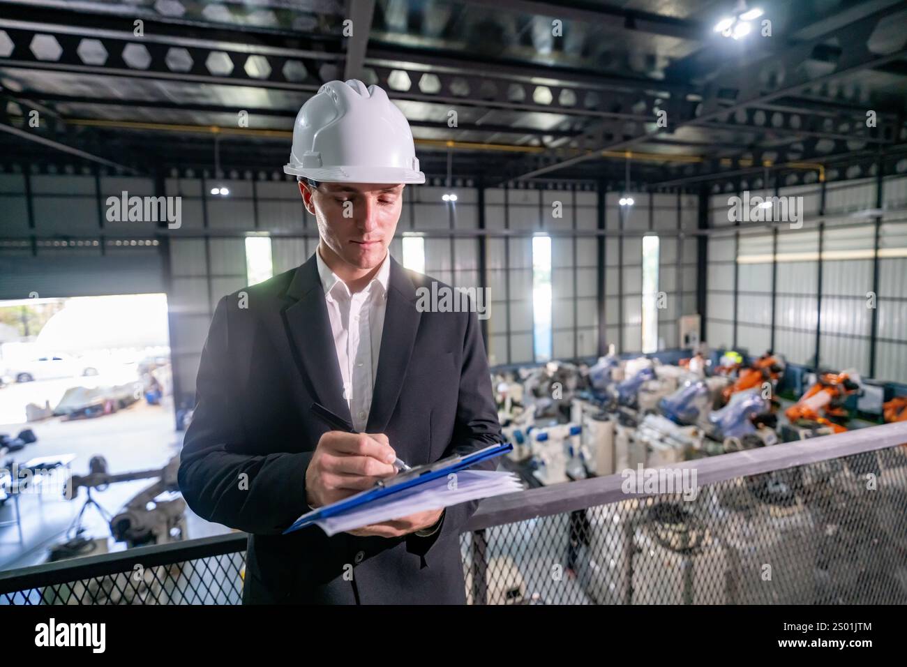 A construction manager in a suit and hard hat reviews notes while ...