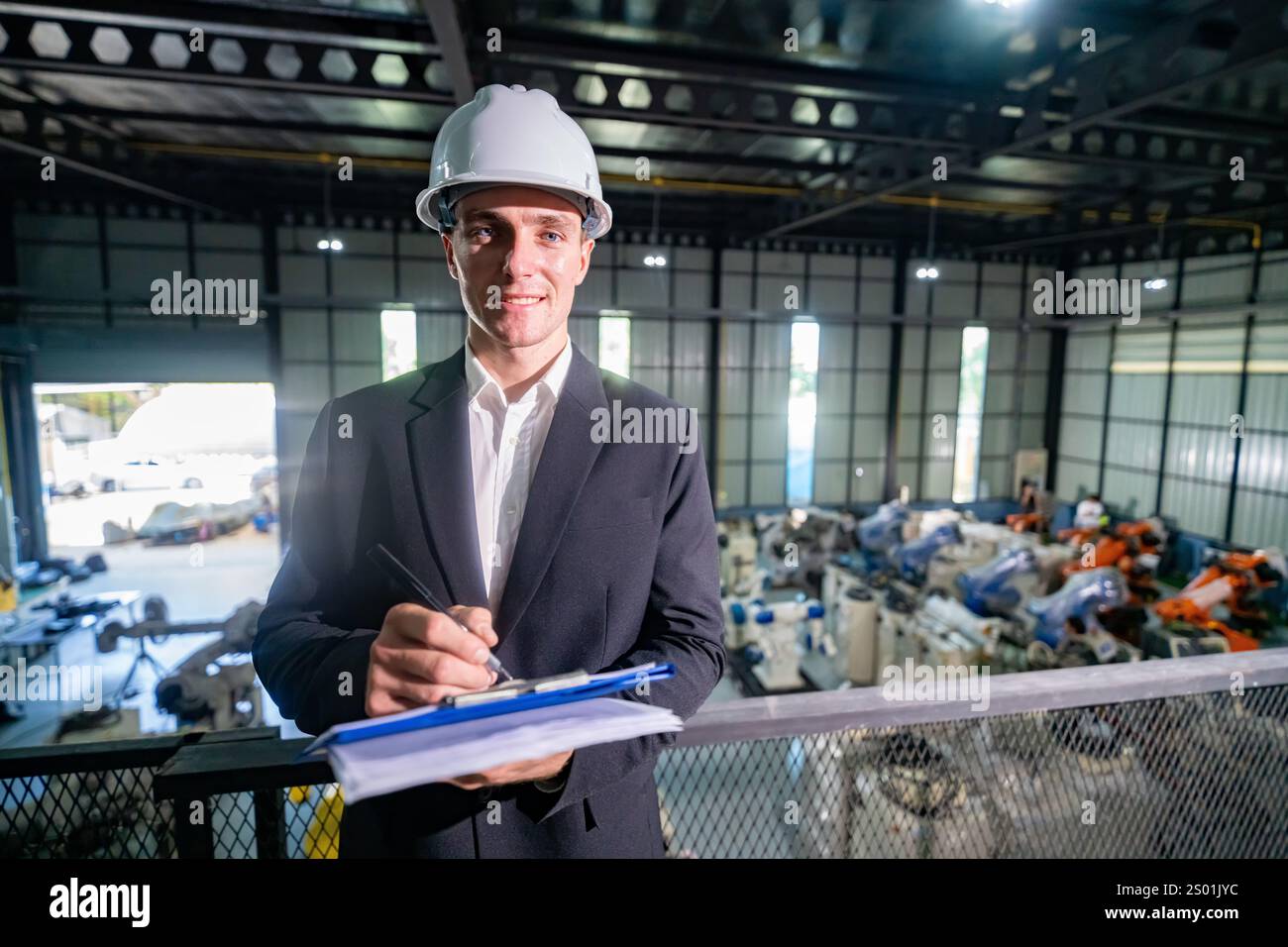 A supervisor in formal attire and safety helmet observes operations ...