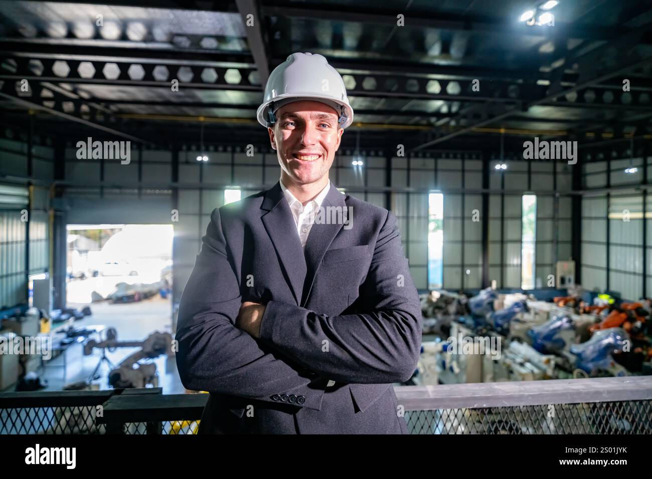 A man dressed in a suit and wearing a hard hat stands confidently with ...