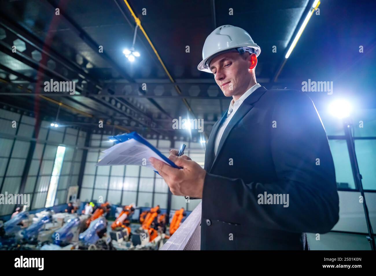 A professional is conducting an inspection of a robotic assembly line ...