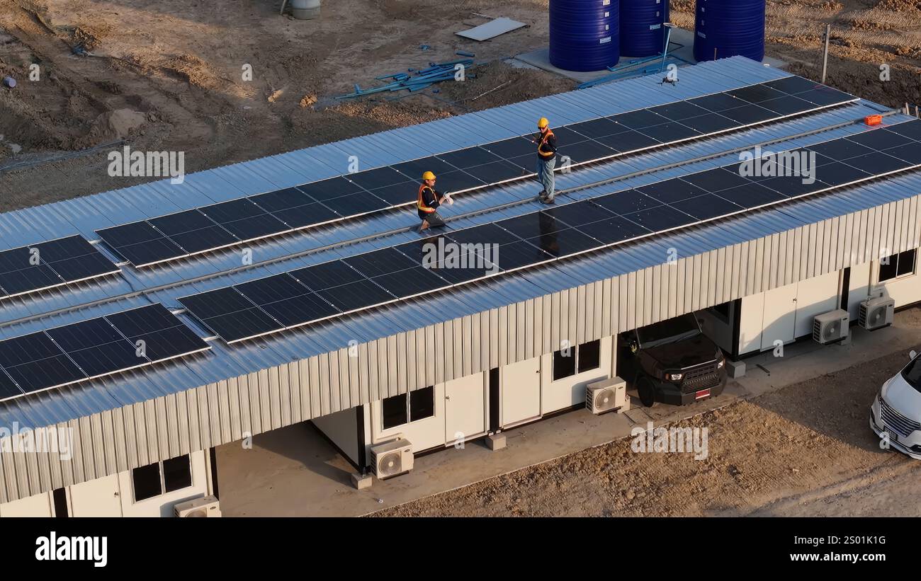 Workers carefully install solar panels on the rooftop of a commercial ...