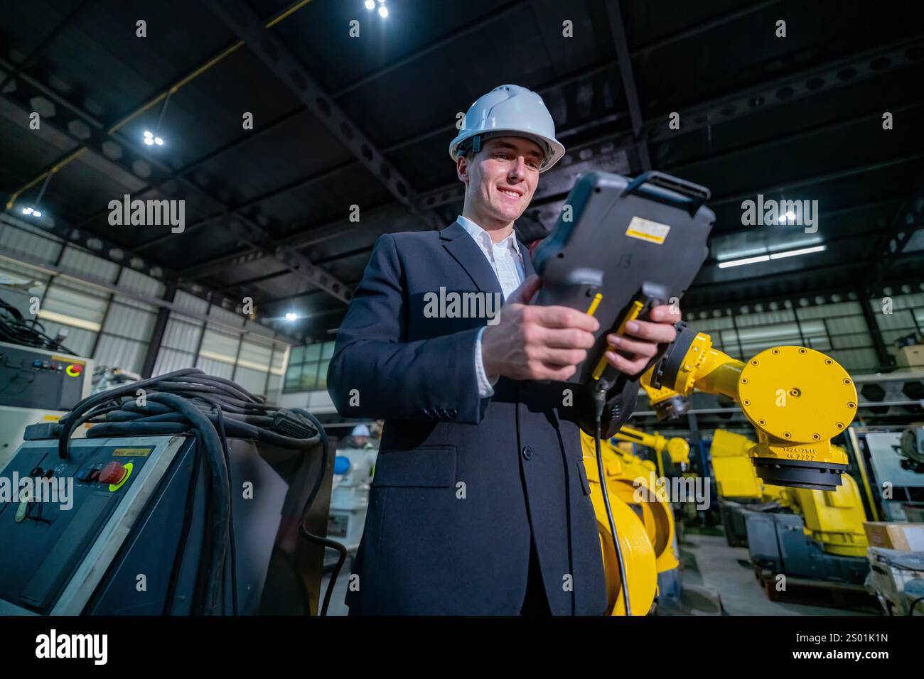 In an advanced manufacturing facility, an engineer in a suit and hard ...