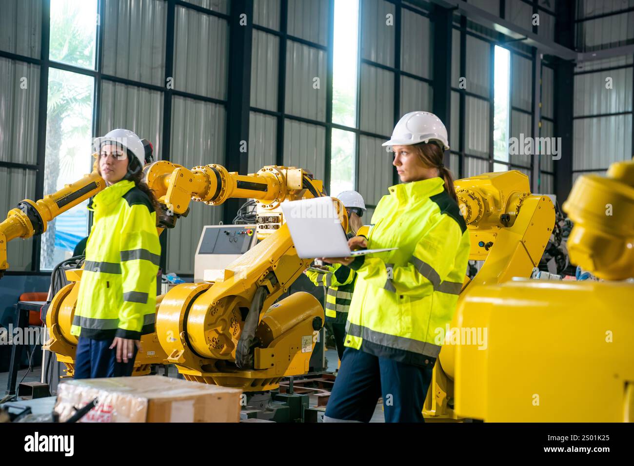 Two engineers in high-visibility jackets and helmets observe and ...