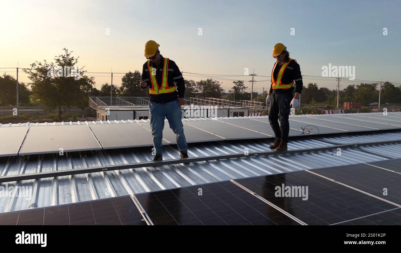 Two workers in safety gear carefully install solar panels on a rooftop ...