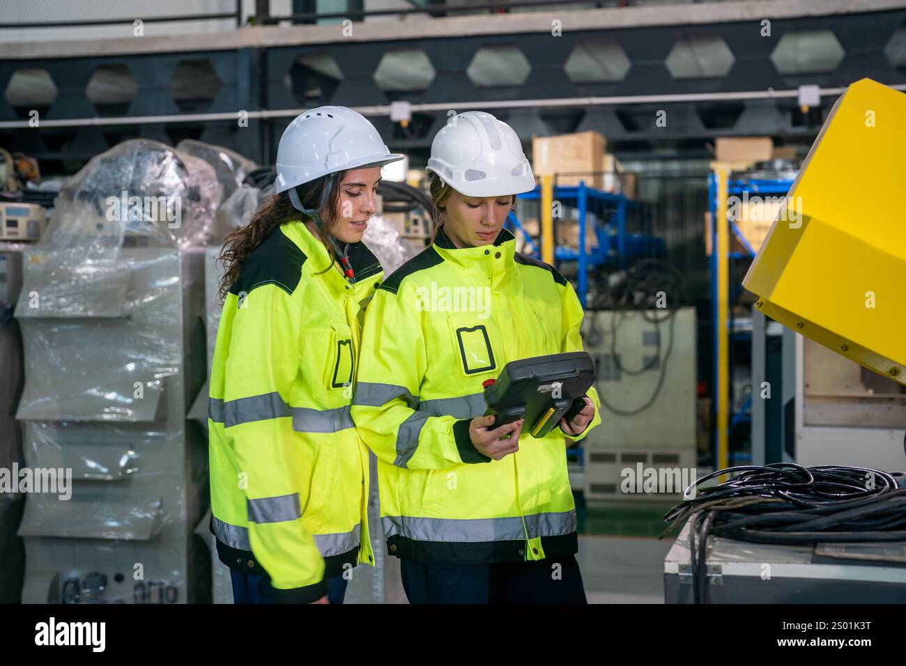 Two workers wearing bright safety gear and helmets are engaged in ...