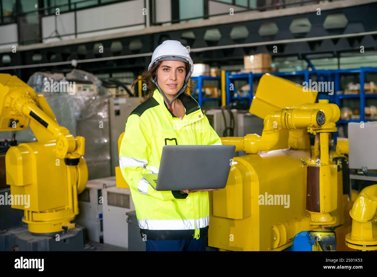 A woman wears a safety helmet and bright jacket while using a laptop in ...