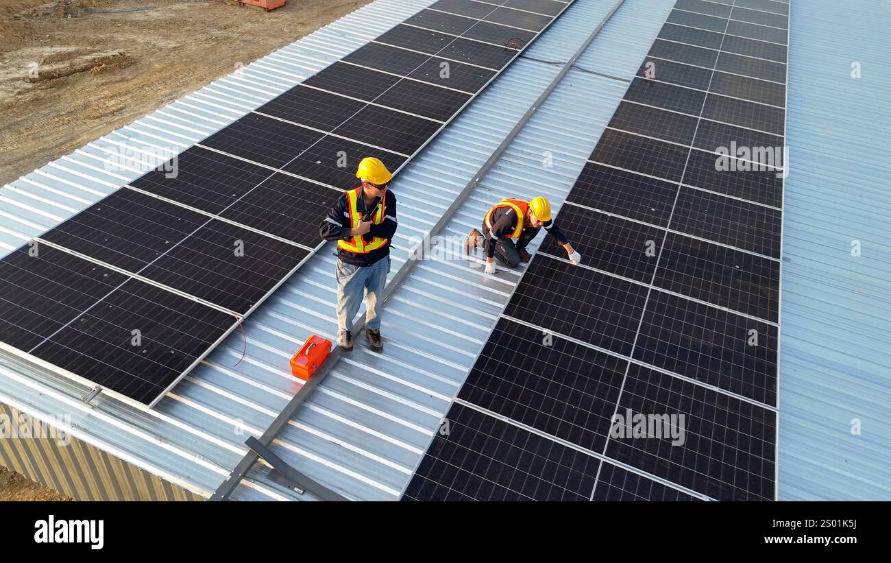 Two workers are installing solar panels on a metal rooftop. One is ...