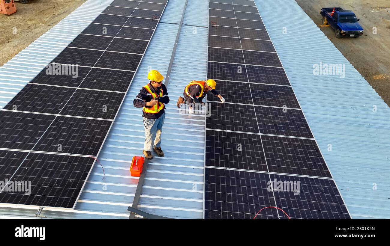 Two construction workers are installing solar panels on a metal rooftop ...