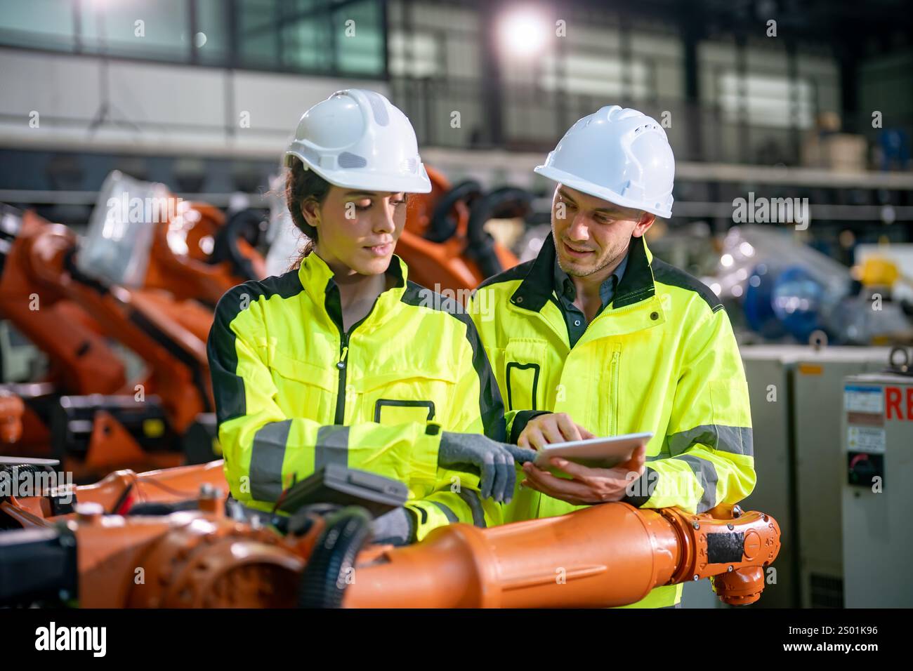 Two engineers wearing safety helmets and bright jackets are discussing ...