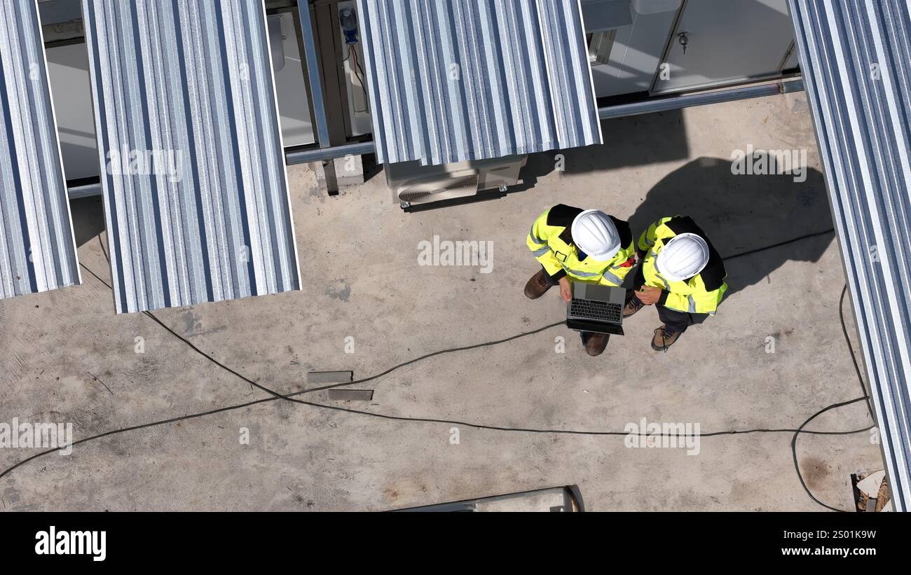 Two construction workers wearing safety helmets and reflective jackets ...