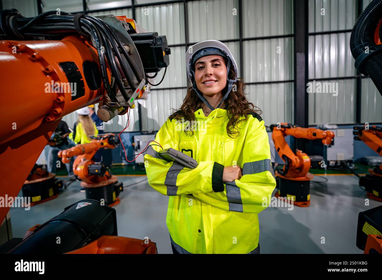 A confident worker in a bright yellow safety jacket and helmet stands ...