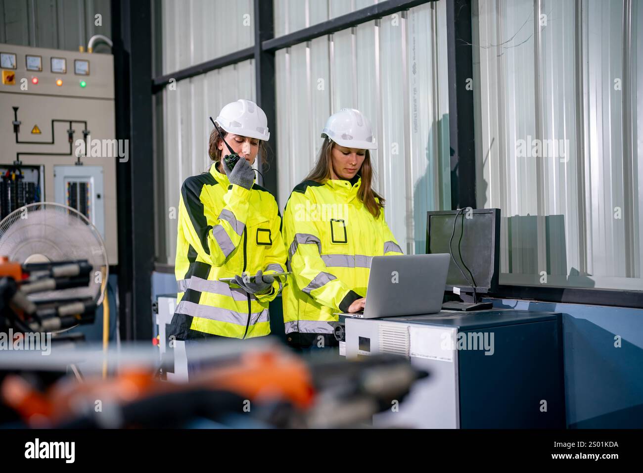 Two engineers wearing safety gear discuss project details in an ...