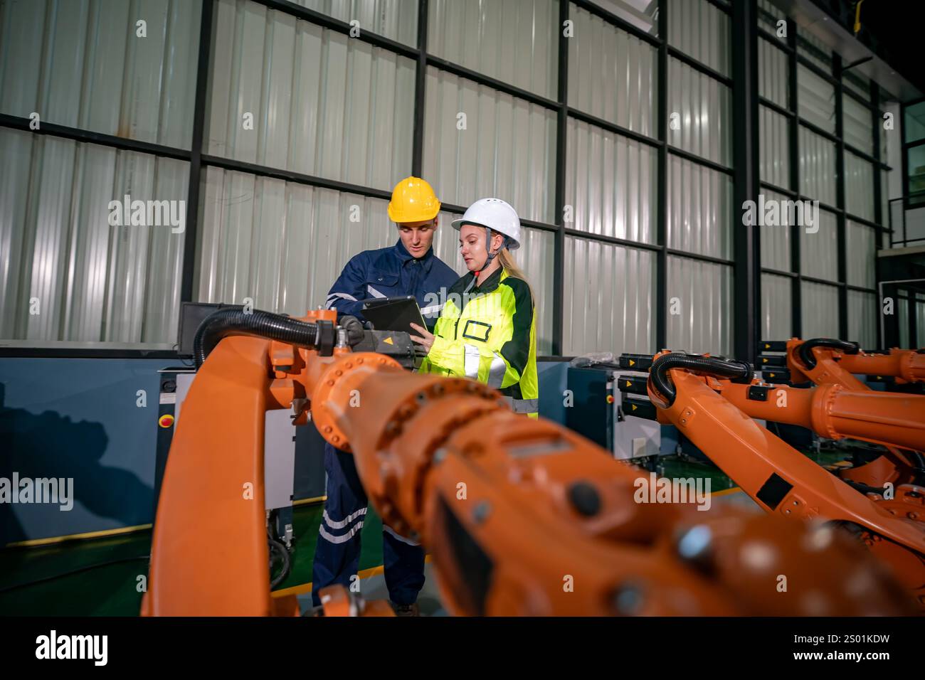 Two engineers are working together in a manufacturing facility ...
