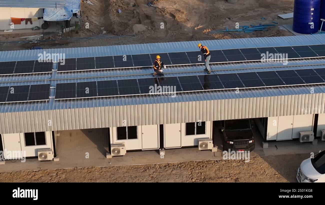 Two workers wearing helmets are seen installing solar panels on the ...