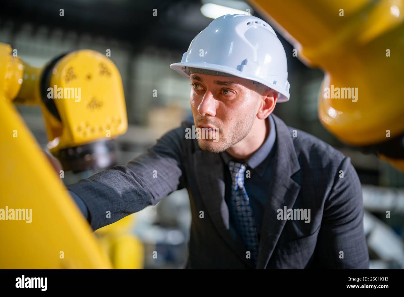 A professional in formal attire carefully examines robotic equipment in ...