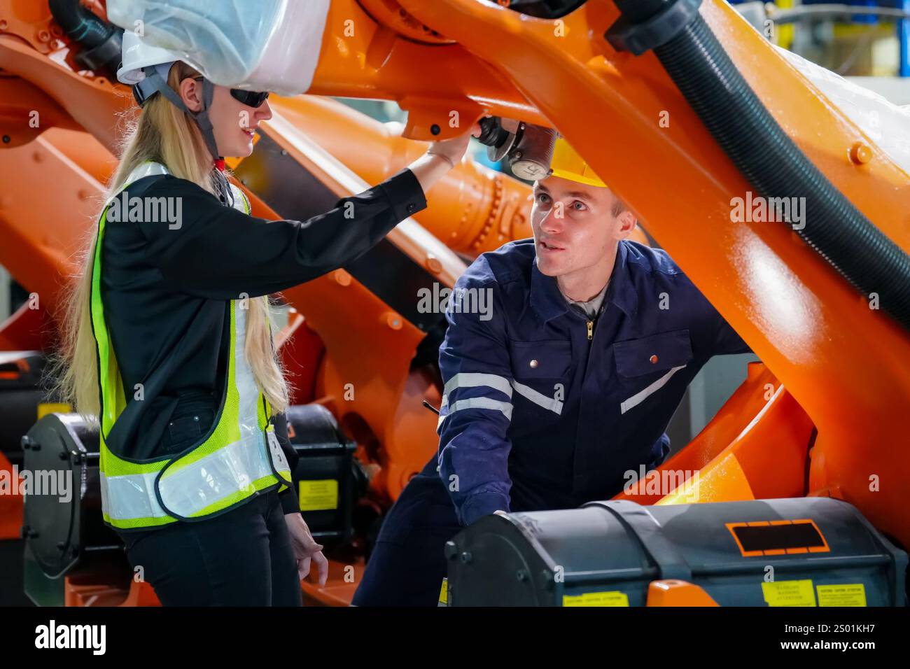 Two technicians engage in maintenance work on robotic equipment inside ...
