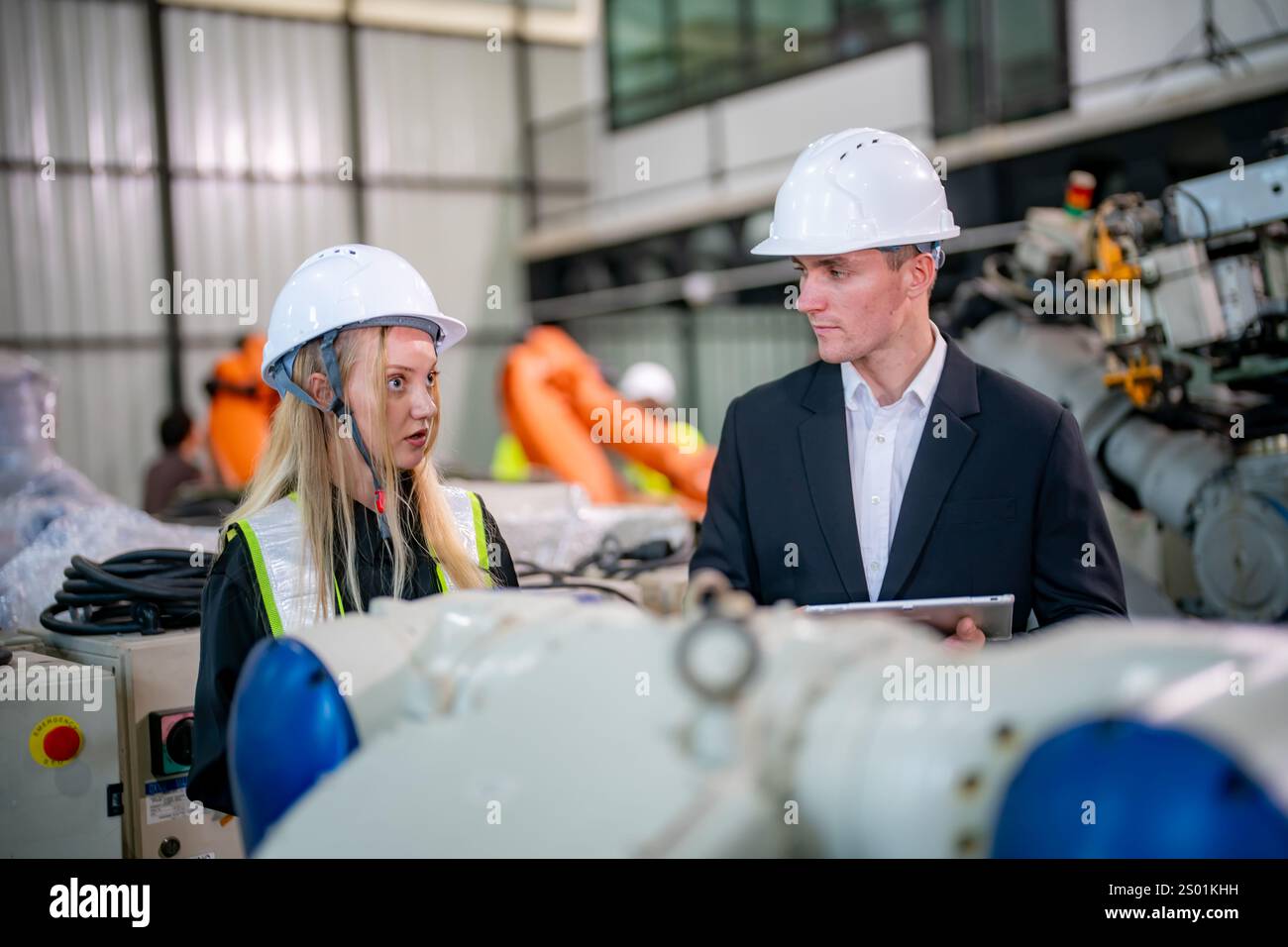 Two professionals engage in conversation while inspecting machinery in ...