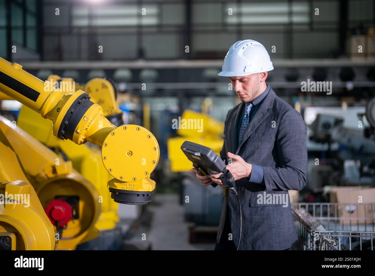 An individual in formal attire inspects a robotic arm in a ...