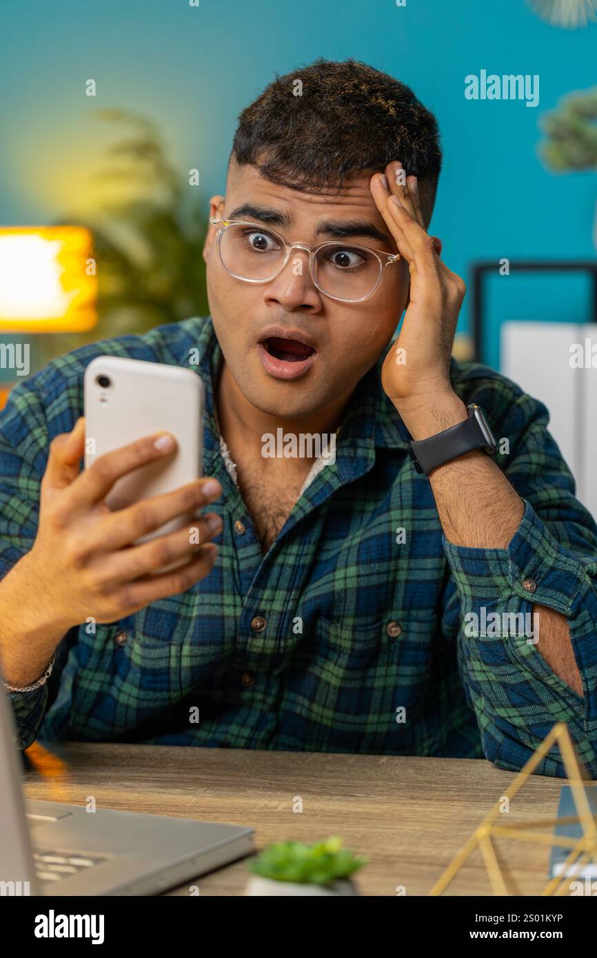 Sad Indian man use smartphone typing browsing, loses becoming surprised ...