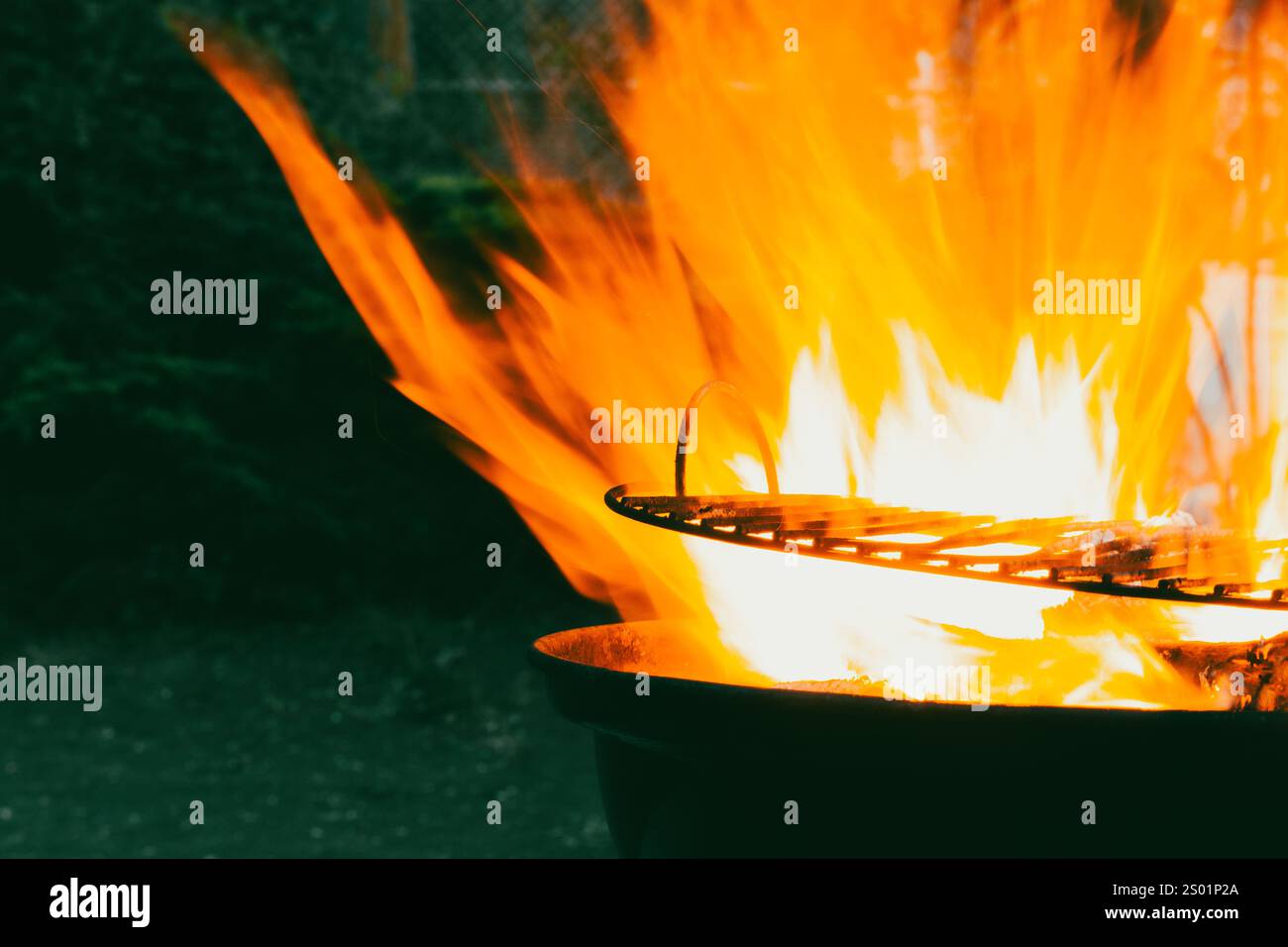 The fire's burning in the brazier. BBQ outdoors at night. Dangerous hot ...