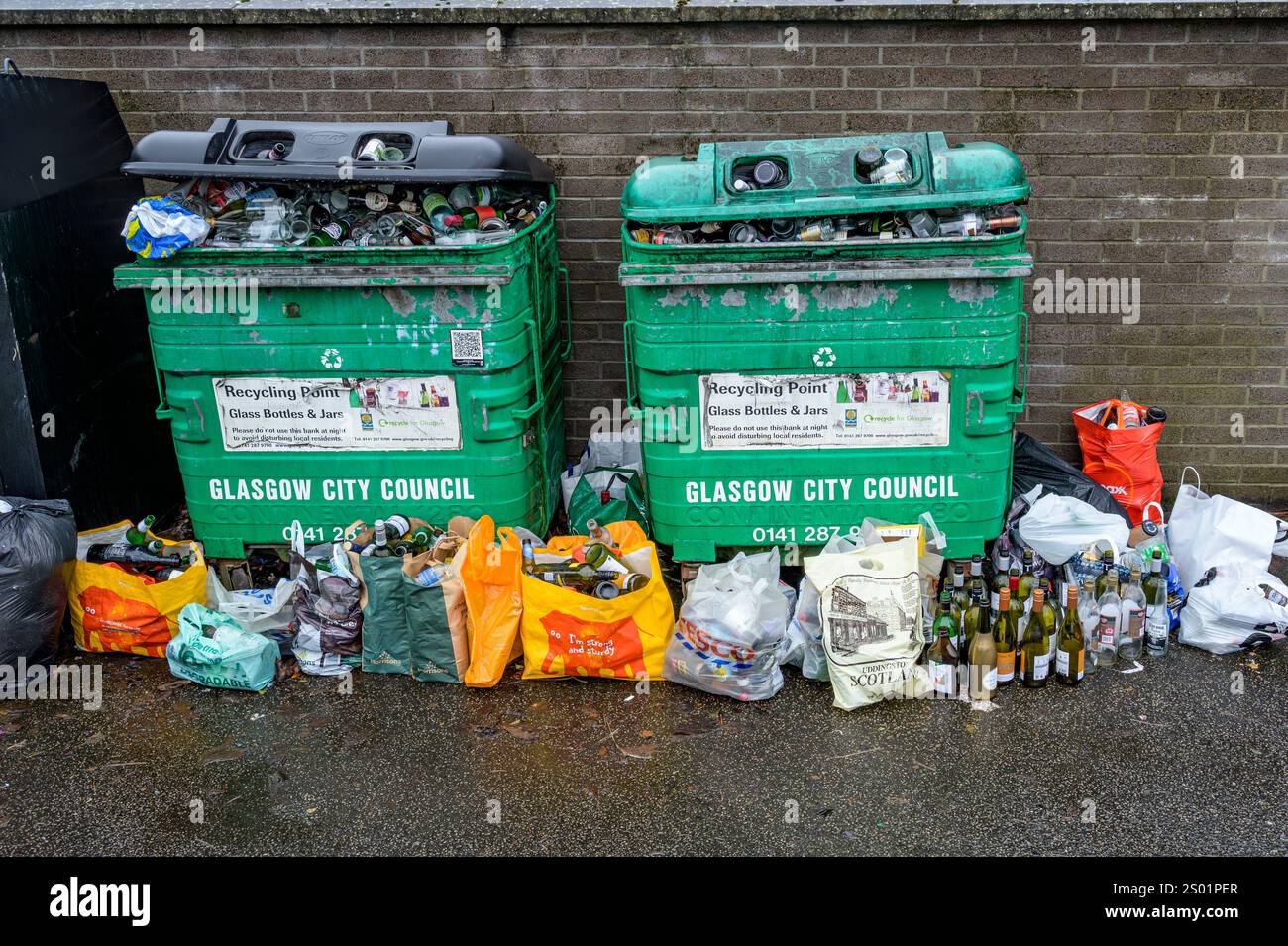 Glass bottles and jars in overflowing bins waiting to be collected from ...