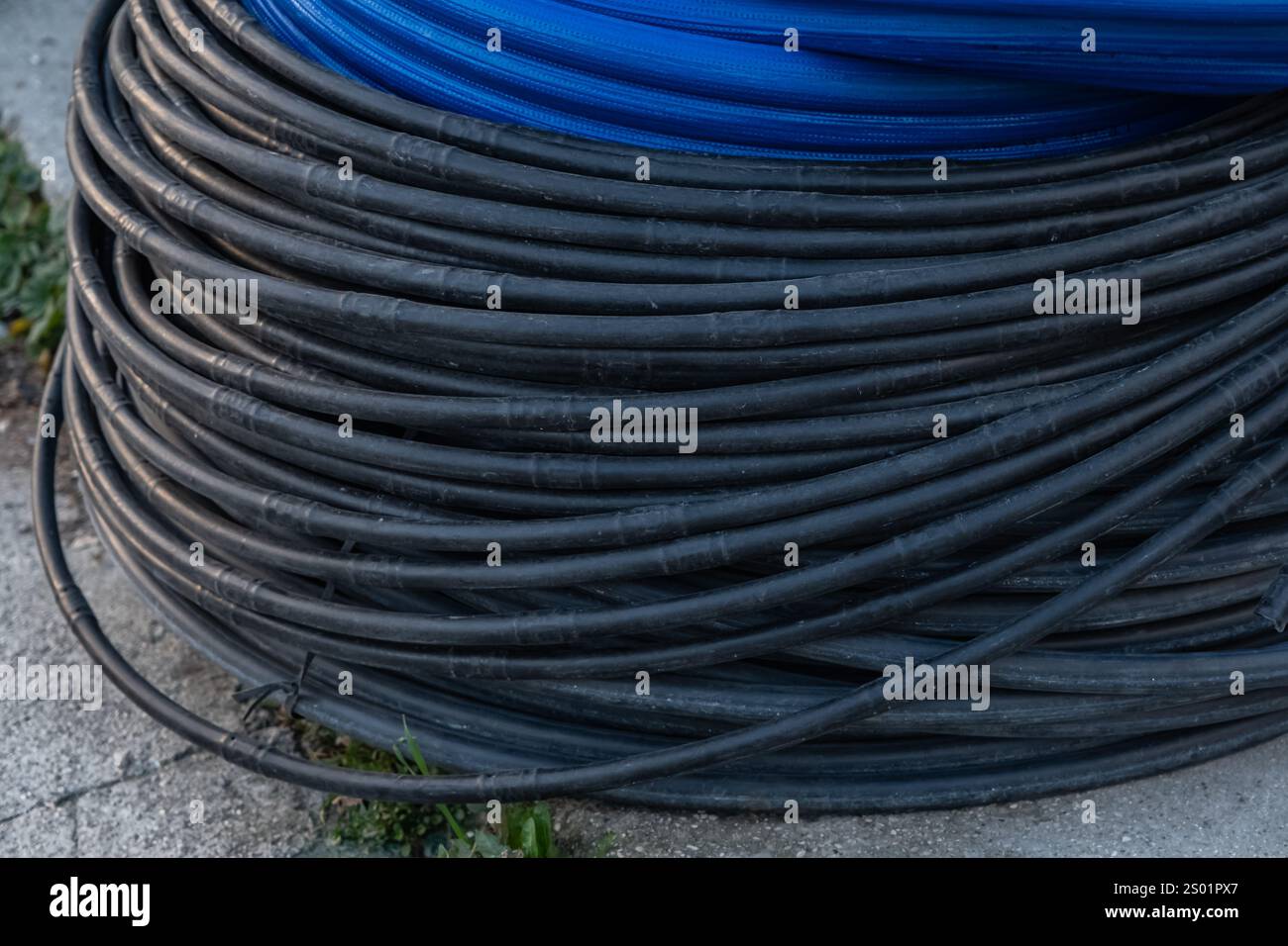 A close-up of a tangled pile of black electrical cables. Rolls of Electrical Wire. High and low ...