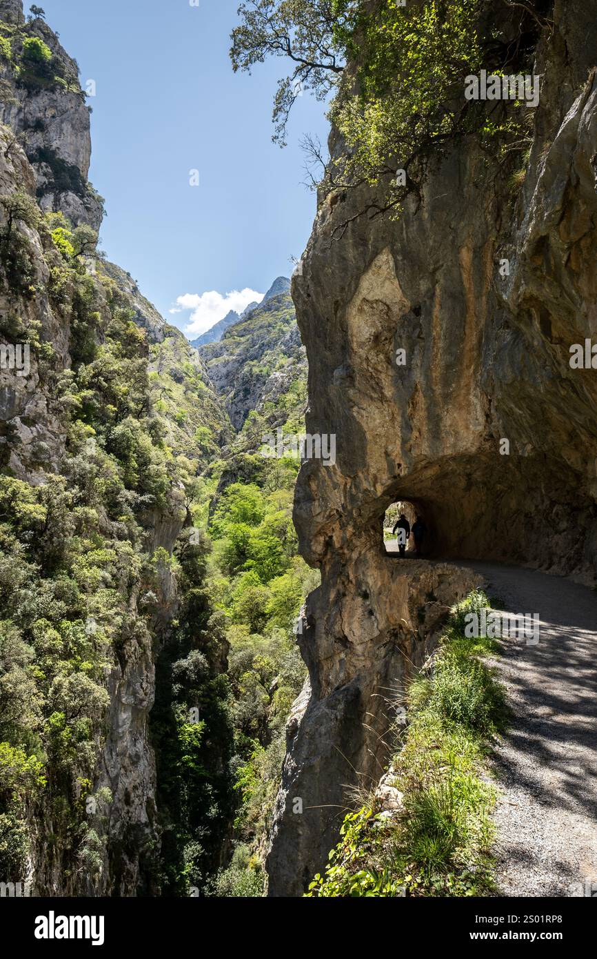 Two tourists walking on cares route trail carved into rock face of ...