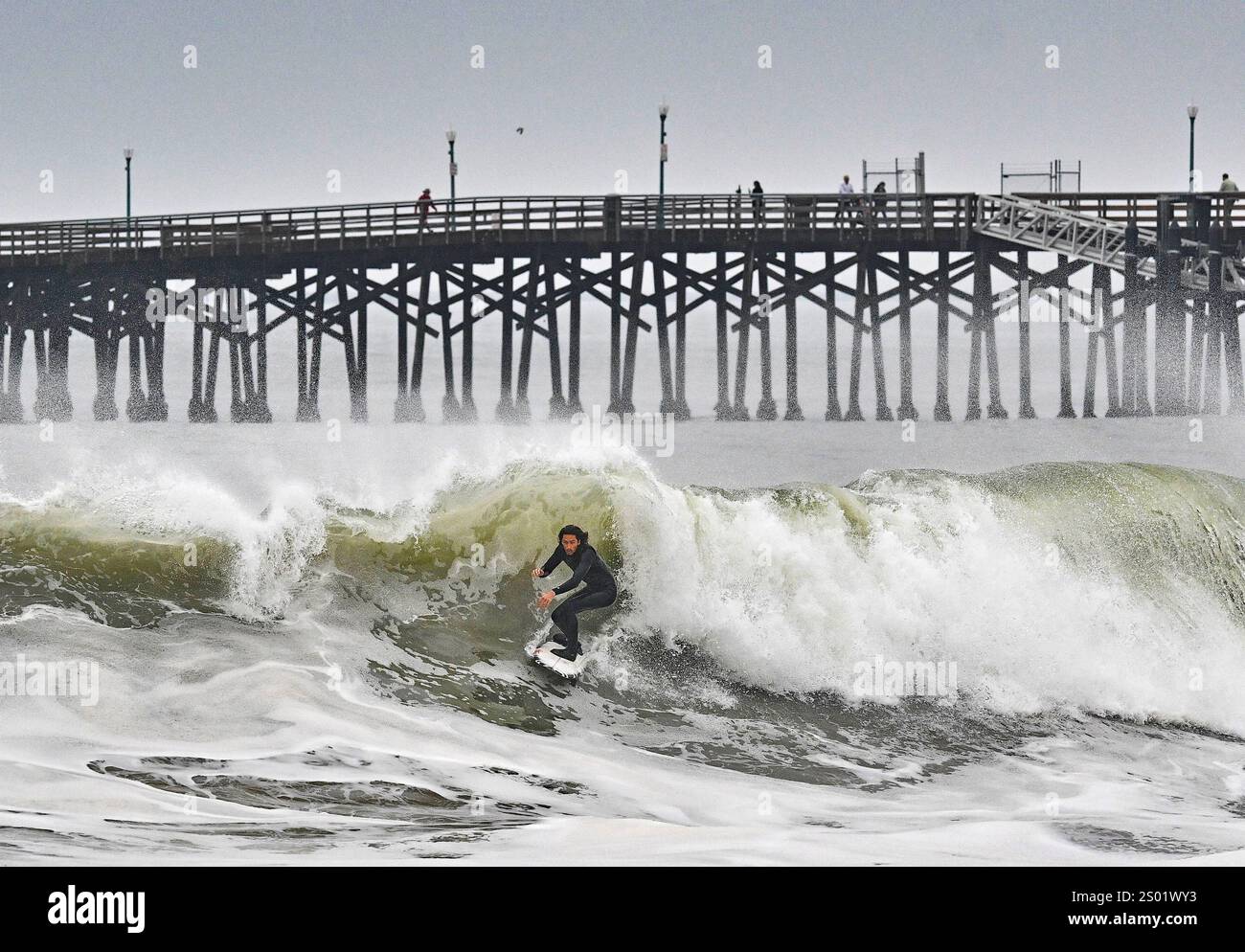 A surfer rides a wave at Seal Beach, Calif., Monday, Dec. 23, 2024 ...