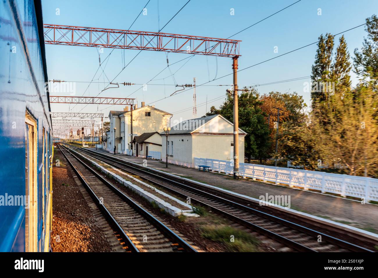 A train is traveling down the tracks with a blue and white train car ...