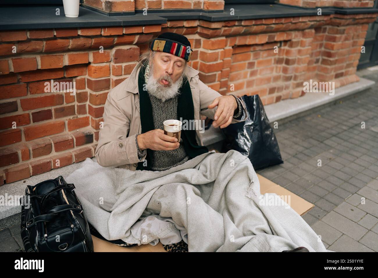 Happy elderly homeless man warming up with cup of coffee on cold urban ...