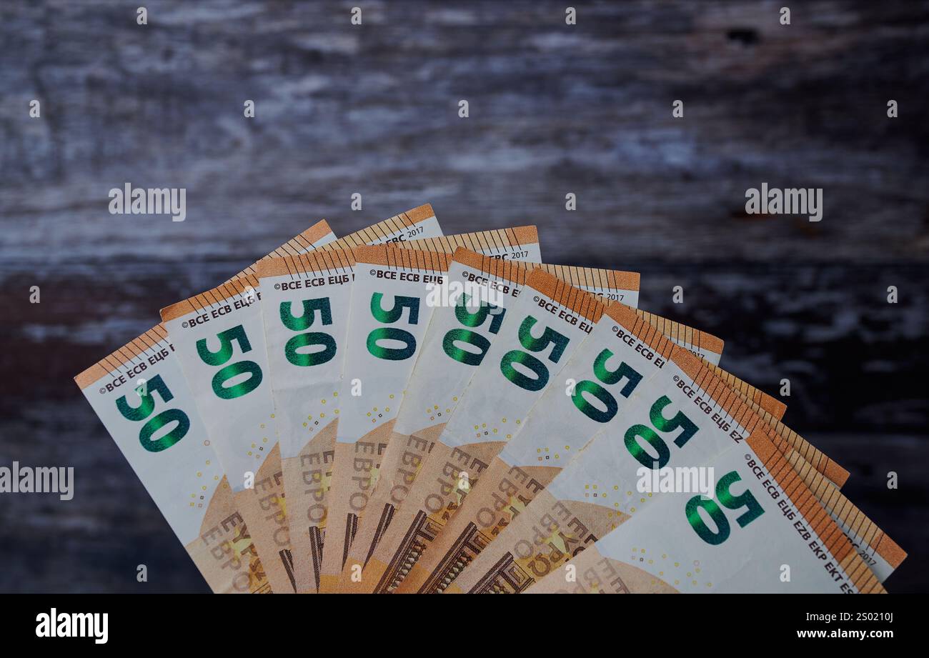 A fan of euros showcases a stack of 50 euro banknotes on wooden surface ...