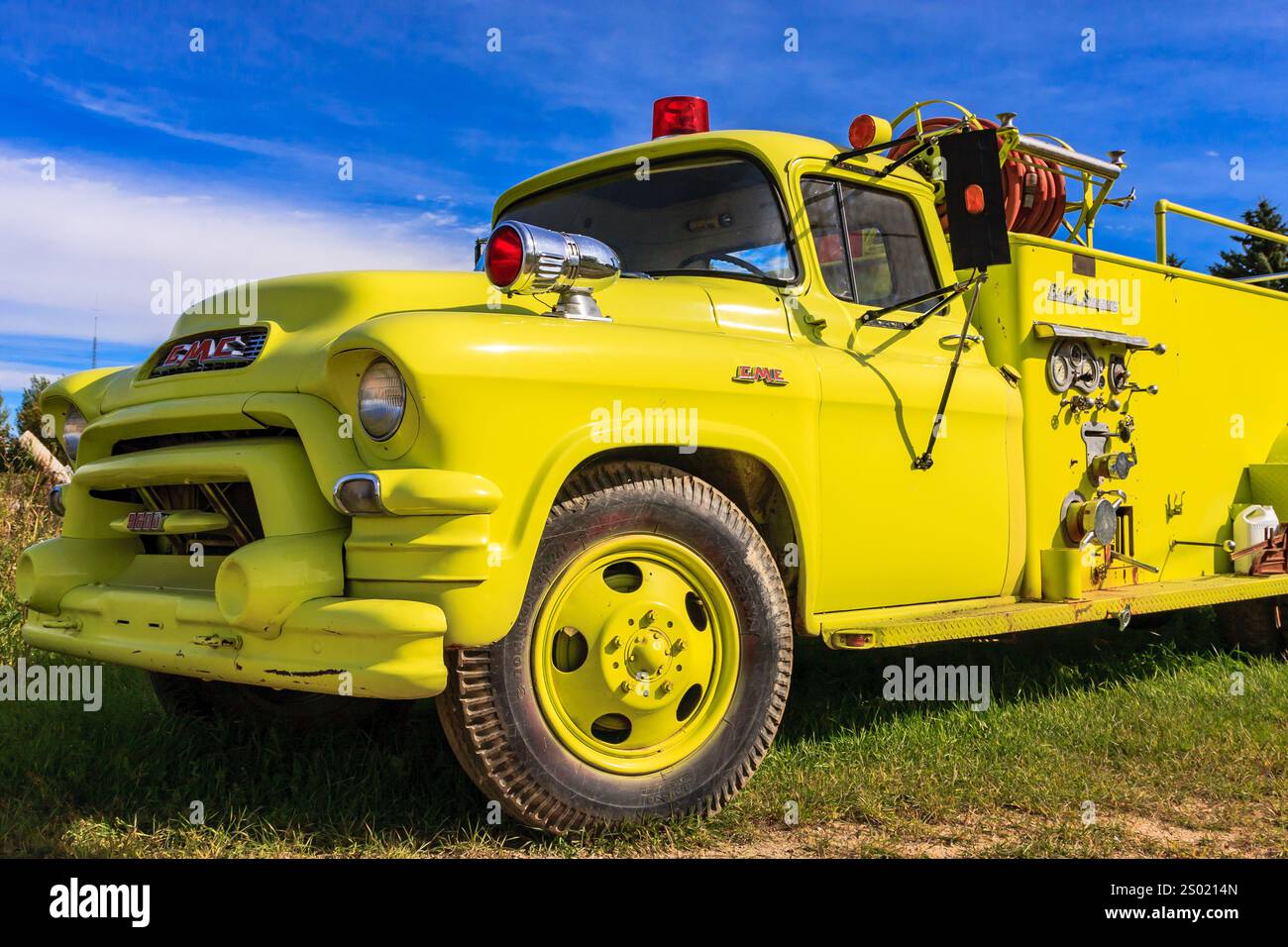 A yellow fire truck with a red light on top. The truck is parked in a ...