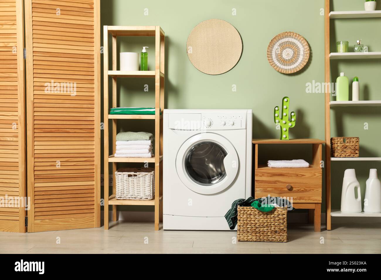 Washing machine, detergents and basket with laundry in room Stock Photo ...