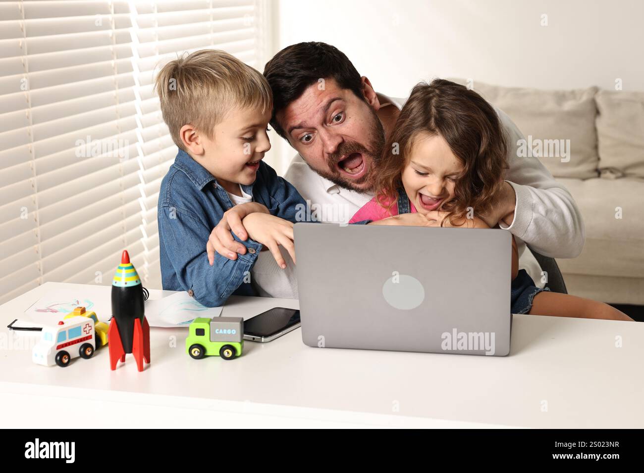 Naughty children disturbing their overwhelmed father at table with ...