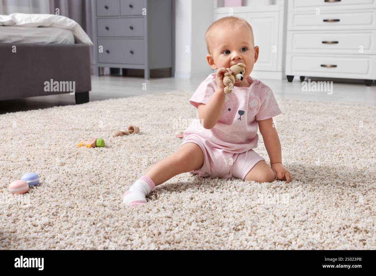 Cute little baby with rattles on floor indoors Stock Photo - Alamy