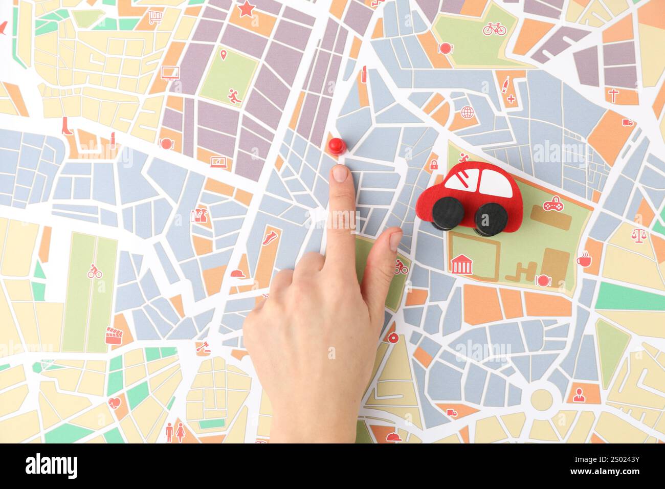 Woman pointing at city map near human figure and toy car, top view ...