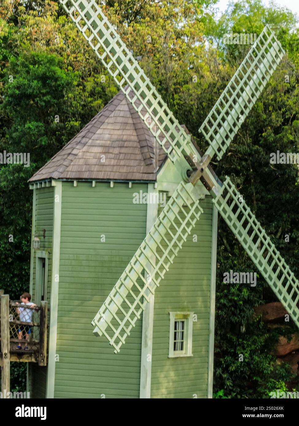 A small green building with a windmill on top. The windmill is old and ...
