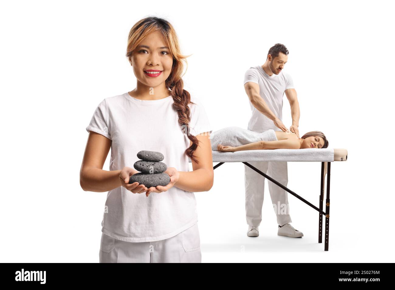 Asian woman holding massage stones and therapist giving a massage to a ...