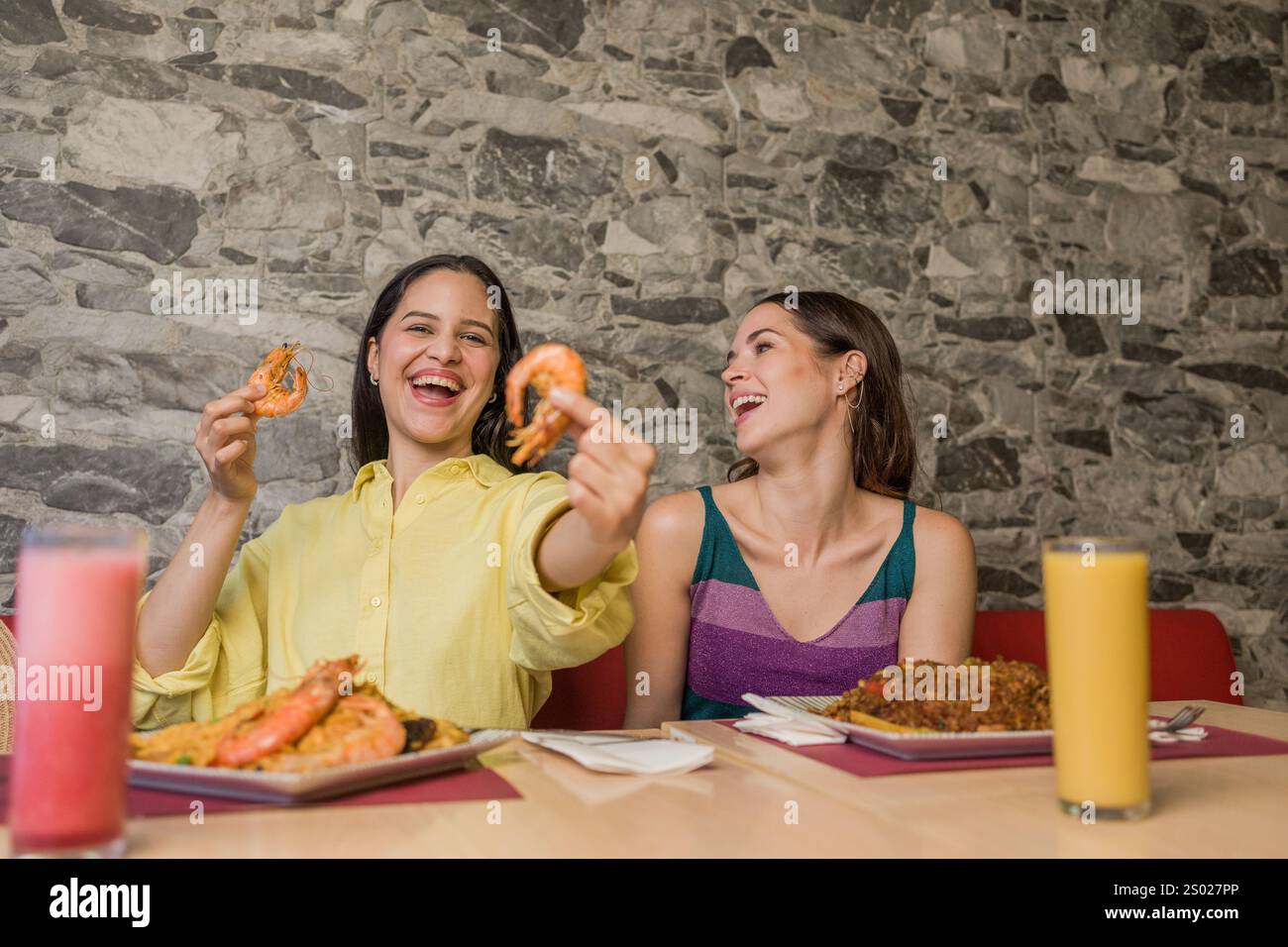 Two smiling women showing shrimps enjoying traditional ecuadorian meal ...