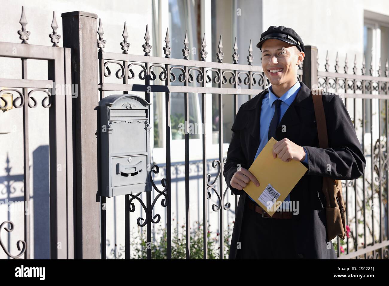 Happy postman with parcel outdoors. Mail service Stock Photo - Alamy
