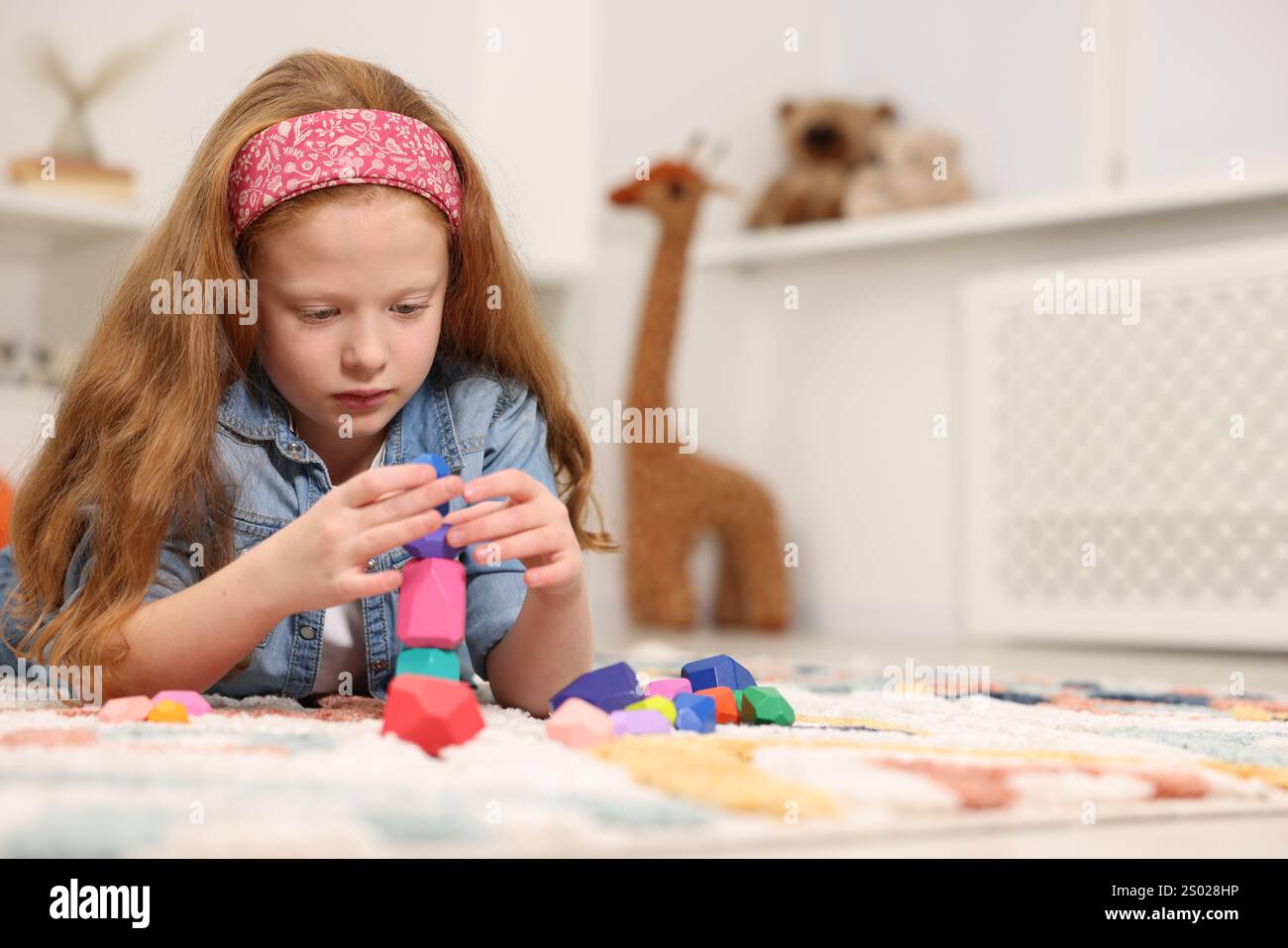 Little girl building tower with balancing stones on floor indoors ...