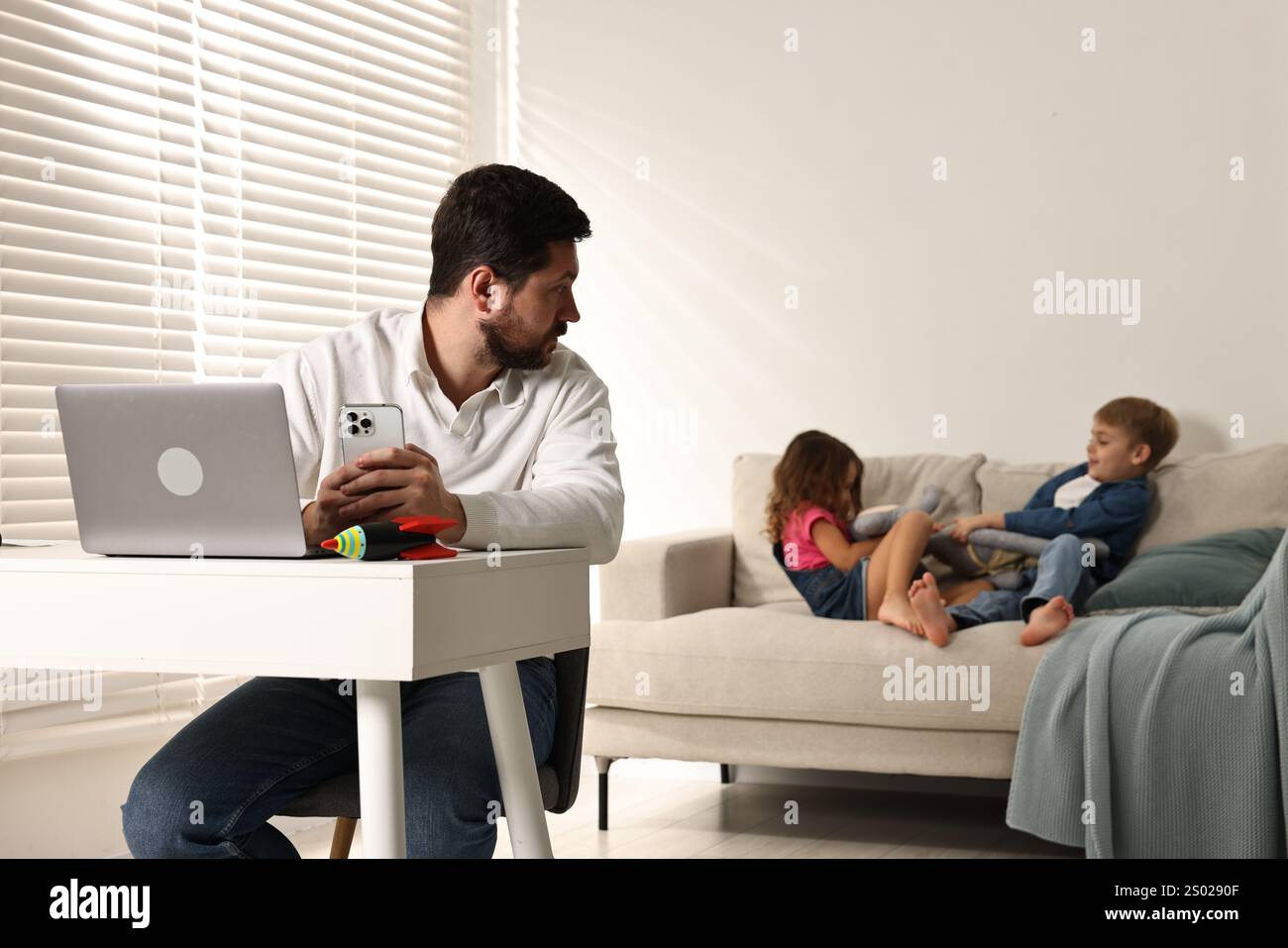 Naughty children disturbing their overwhelmed father at home Stock ...