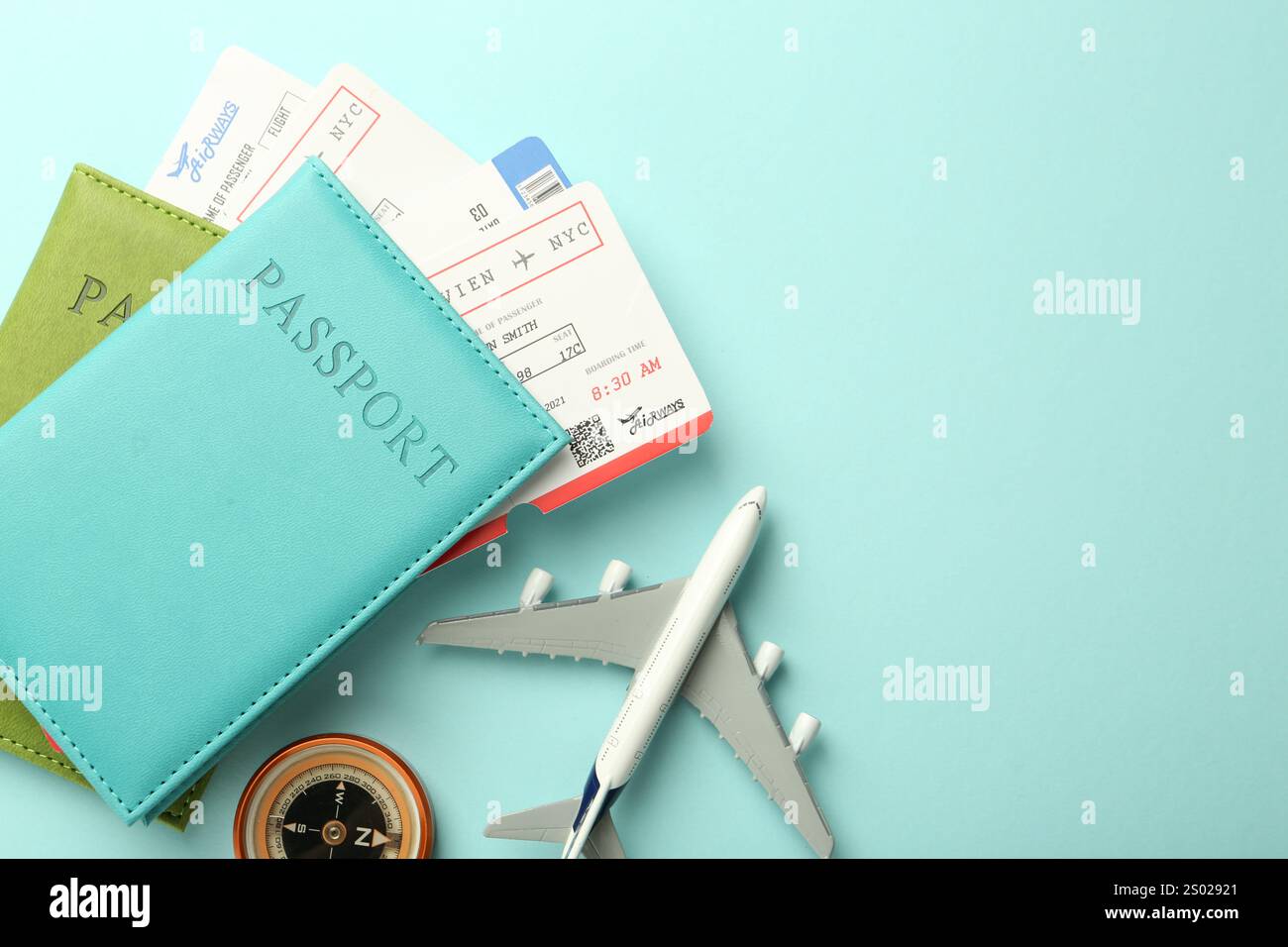 Passport with tickets, compass and plane model on light blue background ...