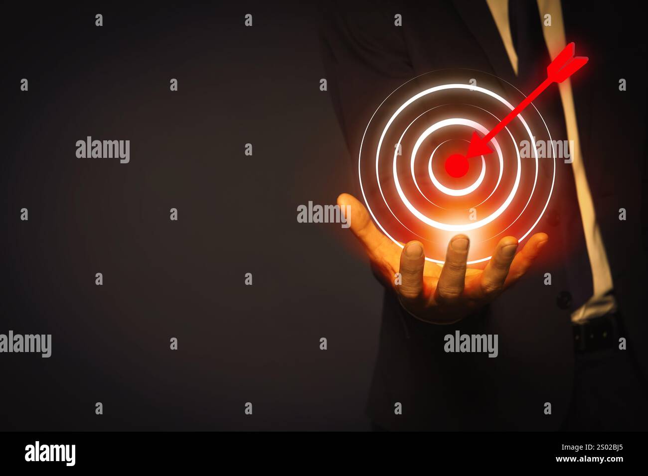 Businessman holding virtual target with arrow on dark background. Goal ...