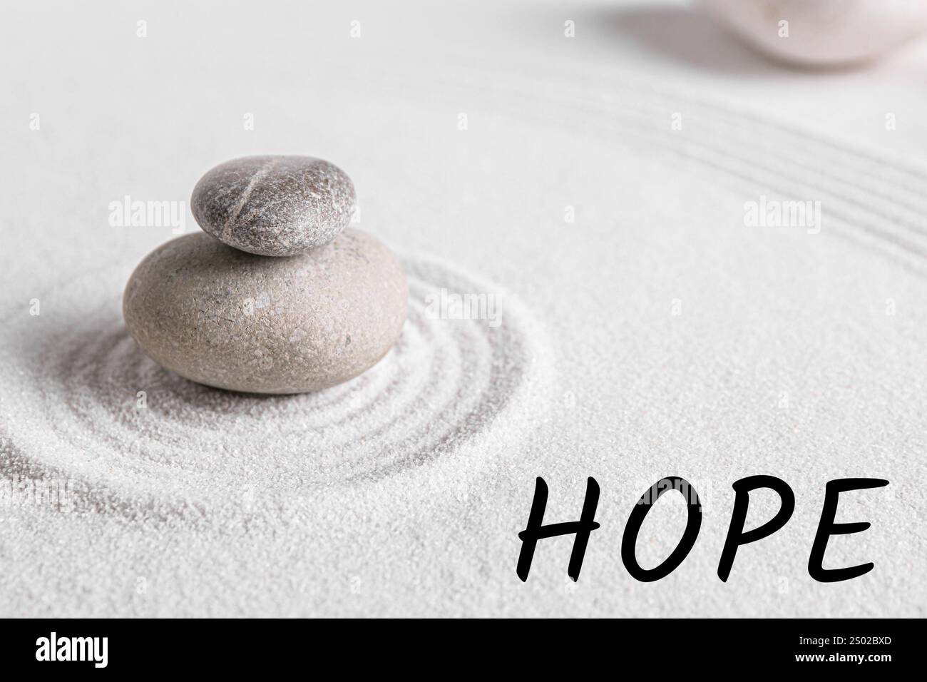 Hope. Zen garden stones on white sand with pattern Stock Photo - Alamy